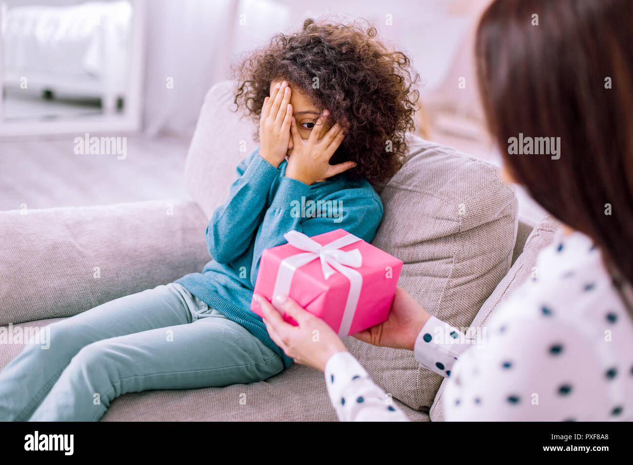 Funny international little female hiding her face Stock Photo - Alamy