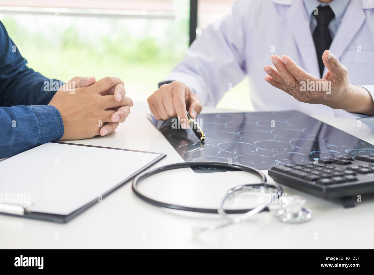 doctor analyzing a scan or x-ray film or explains a CT scan thoughtful ...