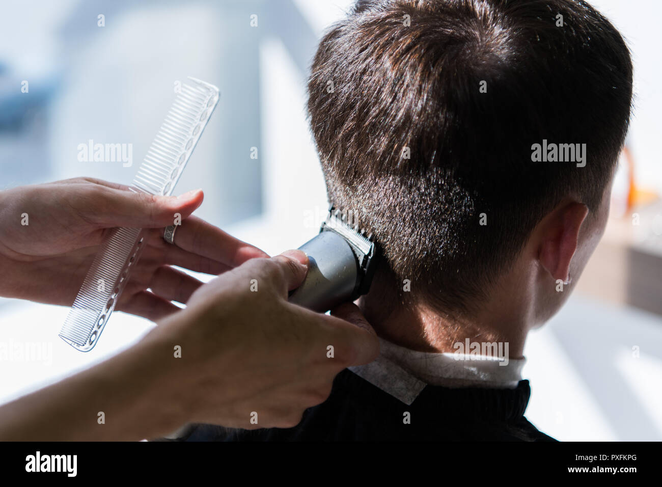 Hairdresser is leveling a haircut with the help of an electric razor ...