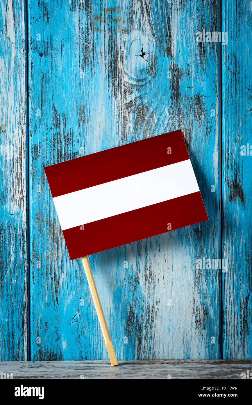 a small flag of Austria on a stick, against a rustic blue wooden ...