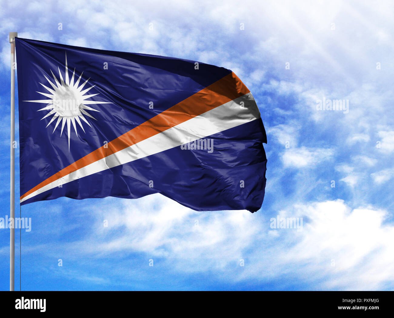 National flag of Marshall Islands on a flagpole in front of blue sky ...
