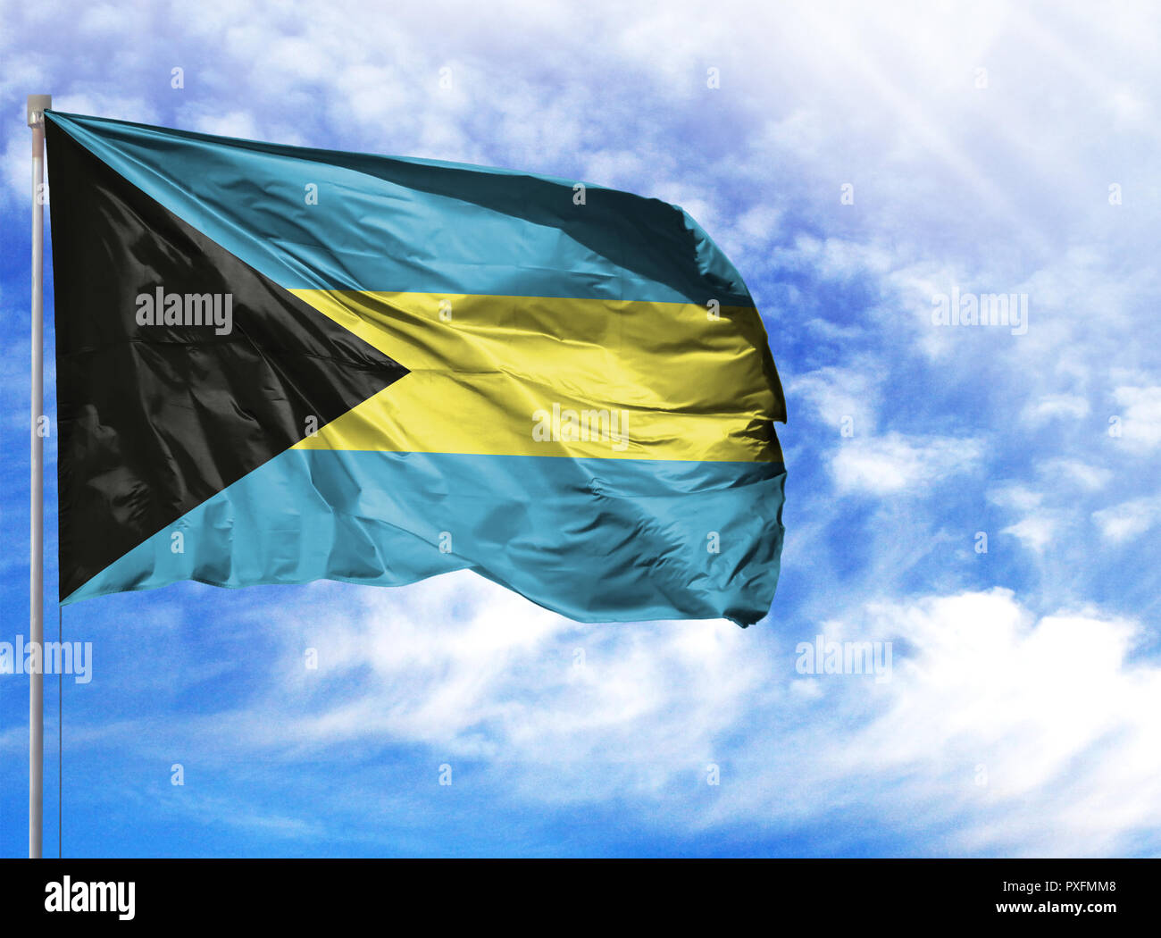 National flag of Bahamas on a flagpole in front of blue sky Stock Photo ...