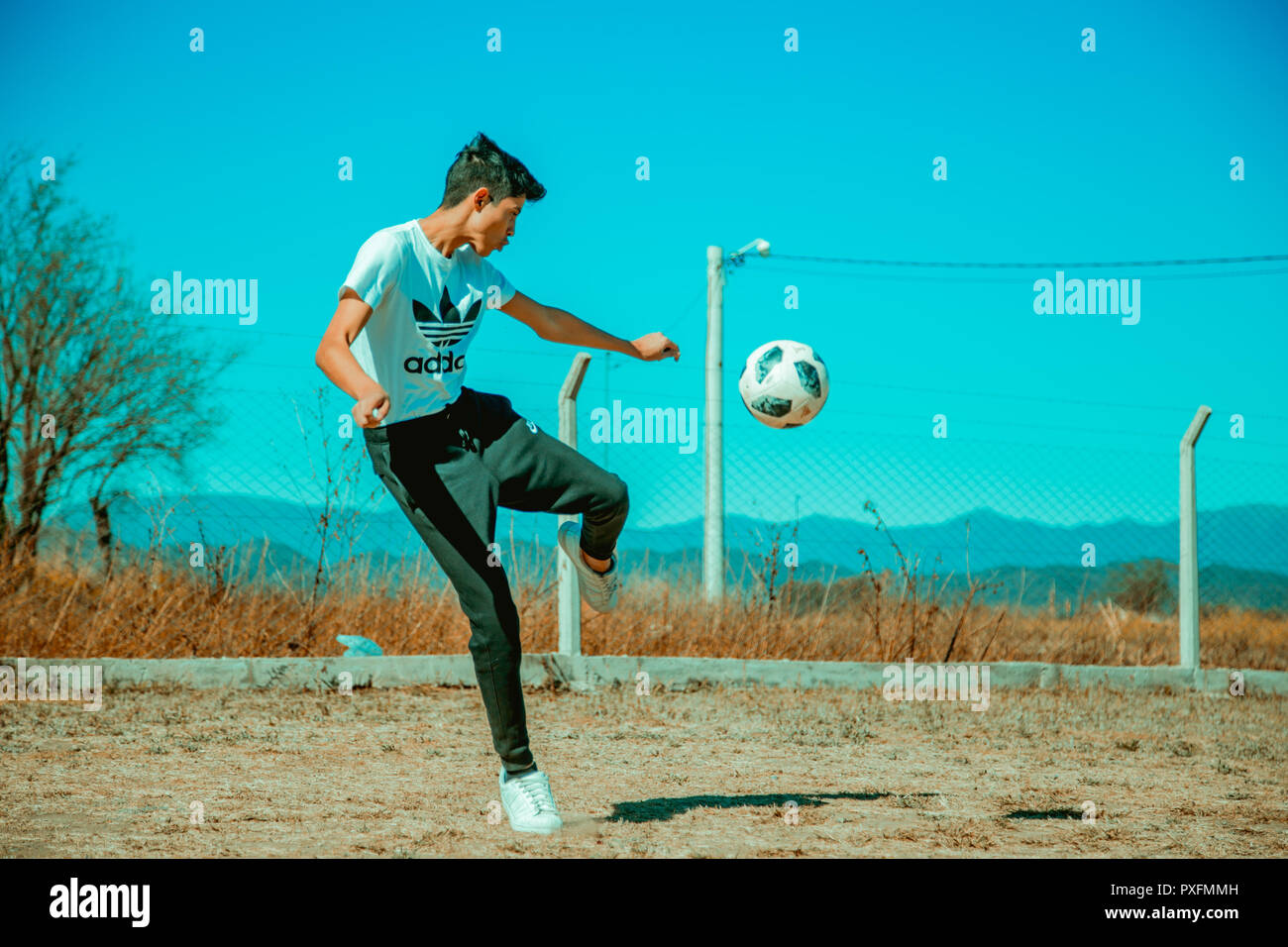 Man playing football soccer on hills Stock Photo - Alamy