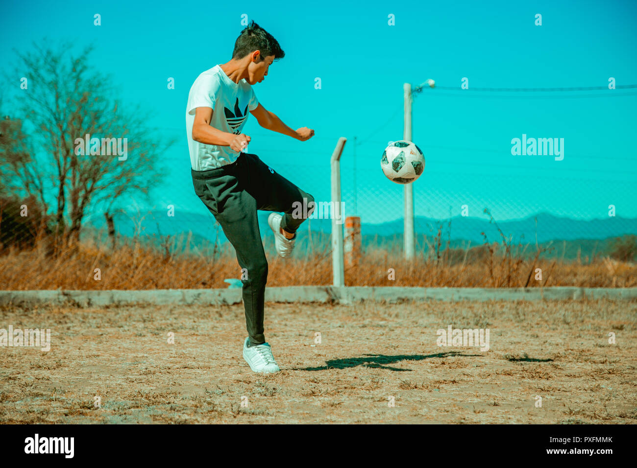 Man playing football soccer on hills Stock Photo - Alamy