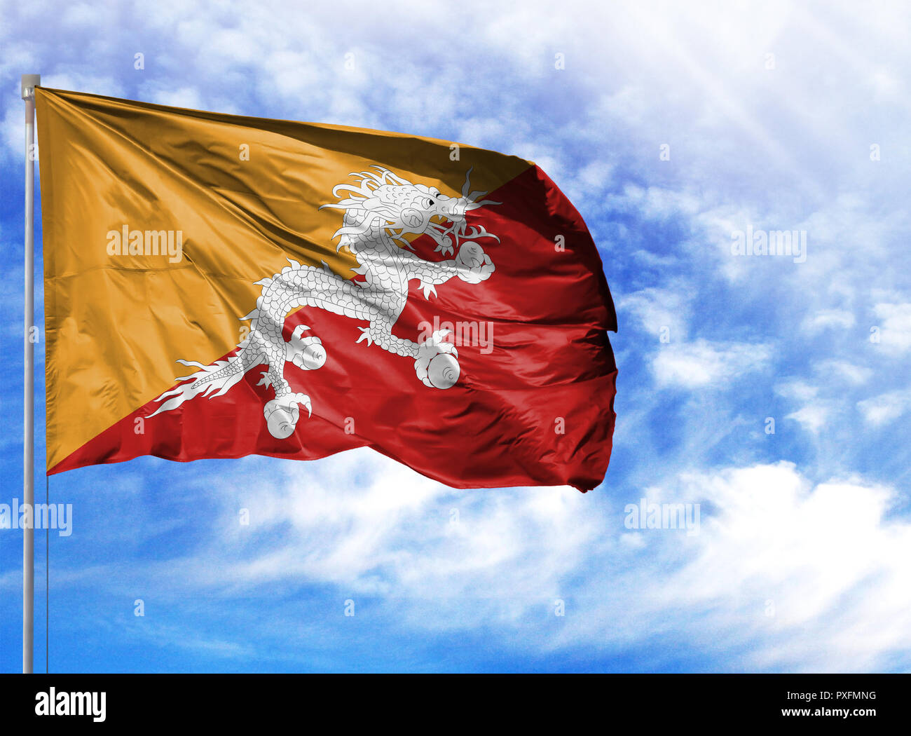 National flag of Butane on a flagpole in front of blue sky Stock Photo ...