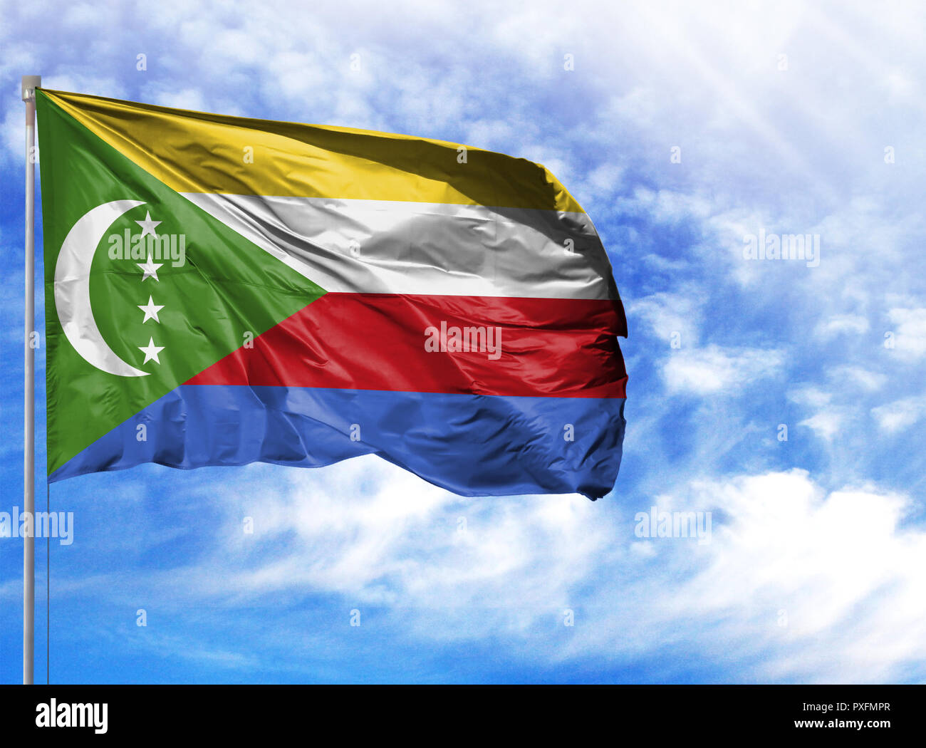 National flag of Comoros on a flagpole in front of blue sky Stock Photo ...