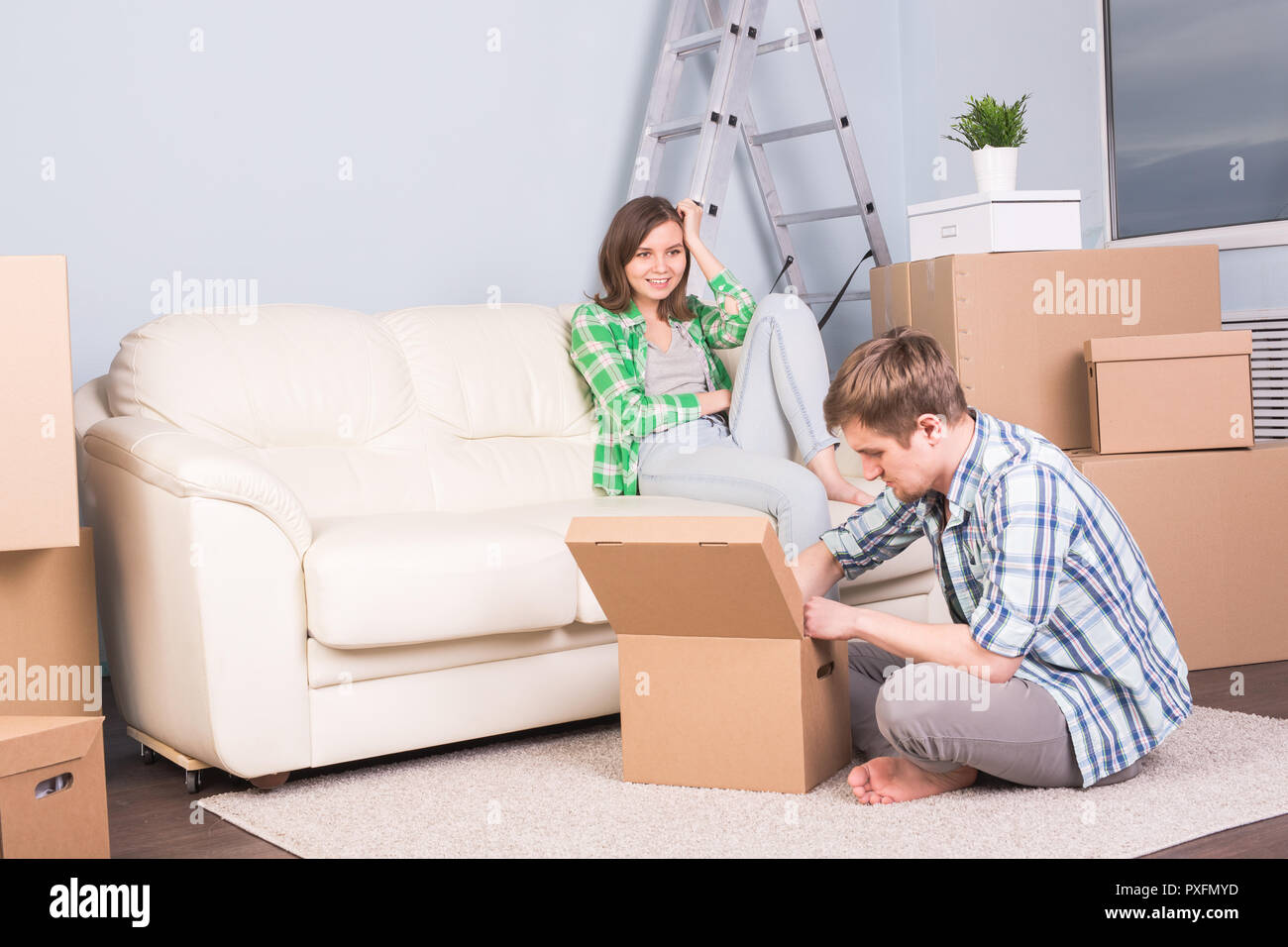 Relocation, new home and real estate concept - Young couple upacking in ...