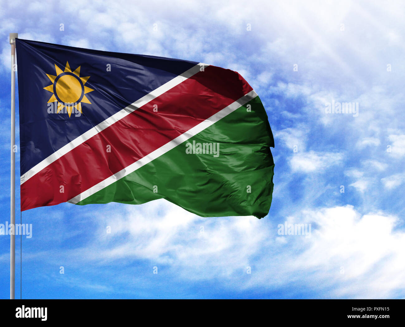 National flag of Namibia on a flagpole in front of blue sky Stock Photo ...