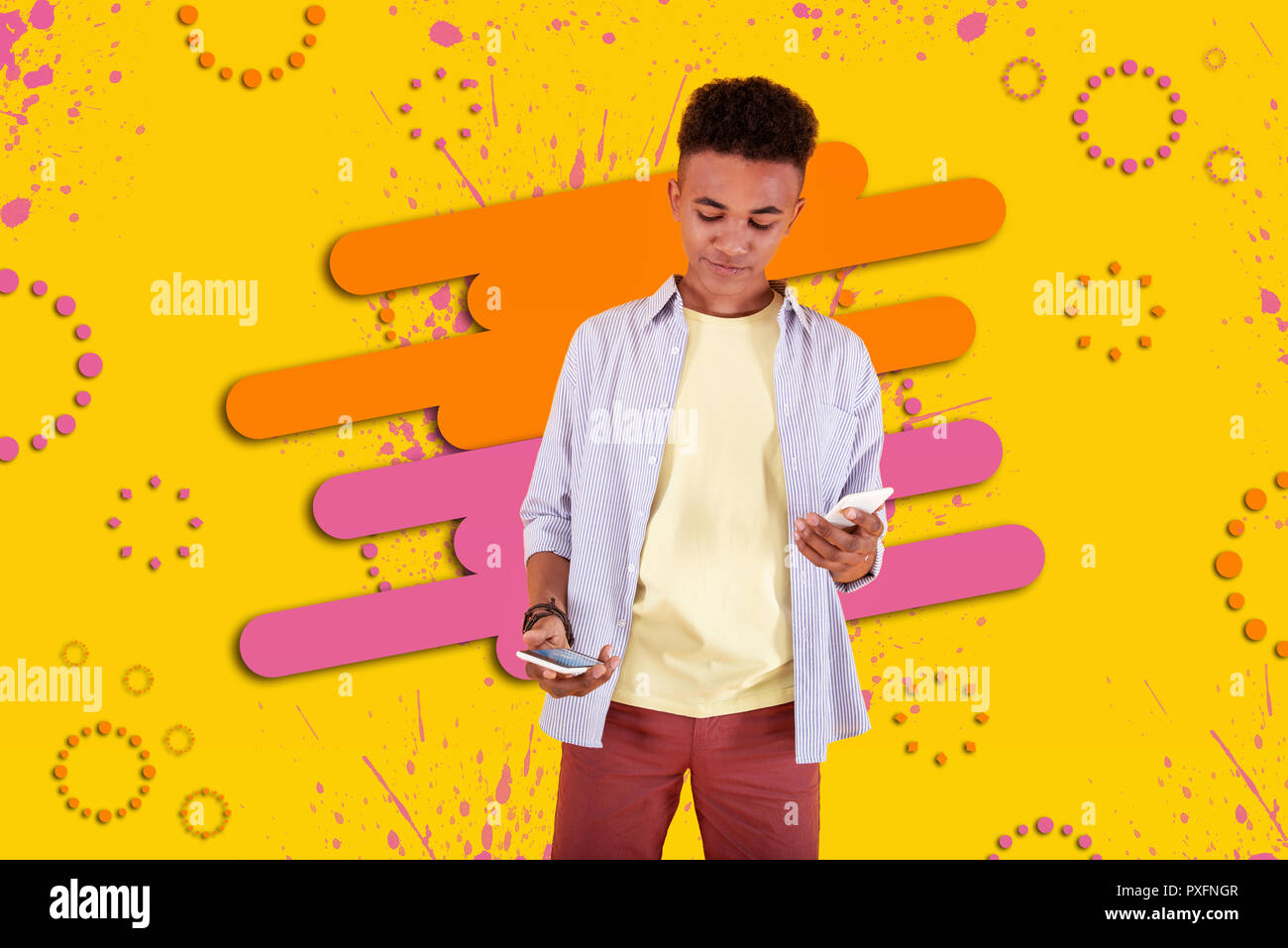 Modern dark-haired boy fond of technology holding two electronic ...