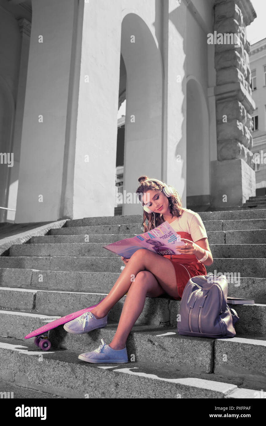 Girl sitting near university while reading magazine getting ready for ...