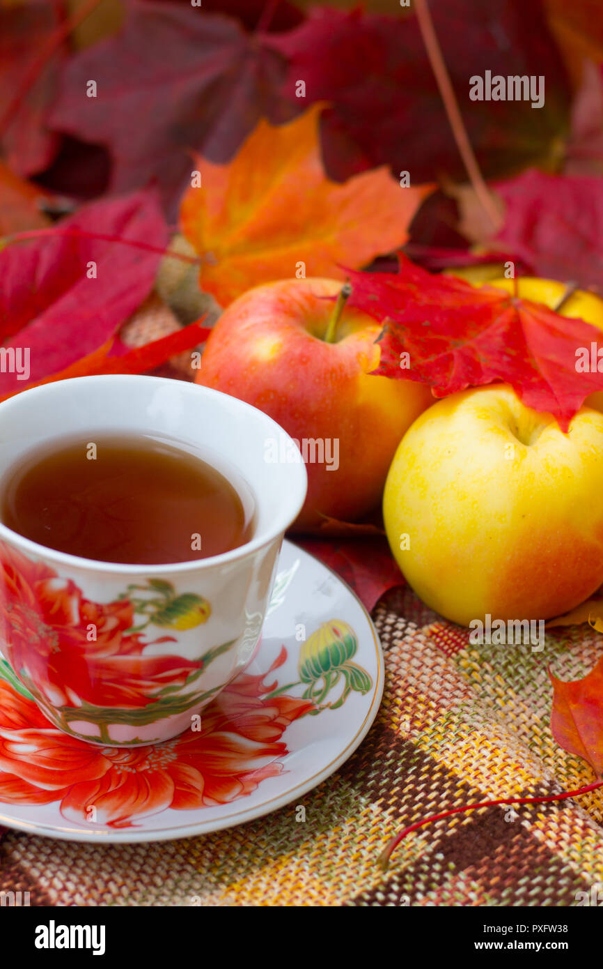 A cup of tea and apples with maple leaves. Autumn tea party, autumn ...