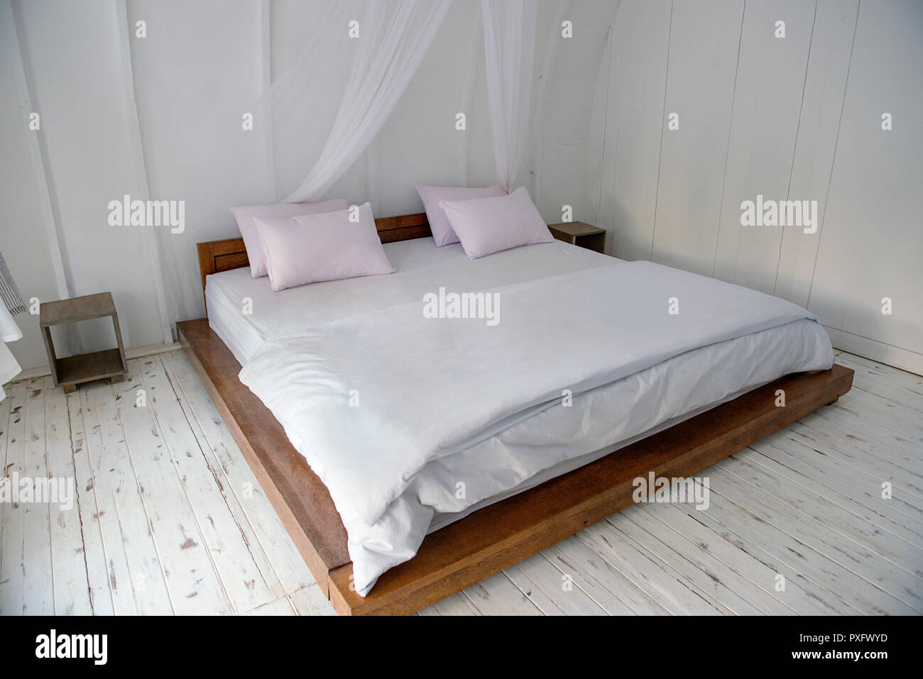 Interior of wooden cottage with large bed and white wall. Wooden ...