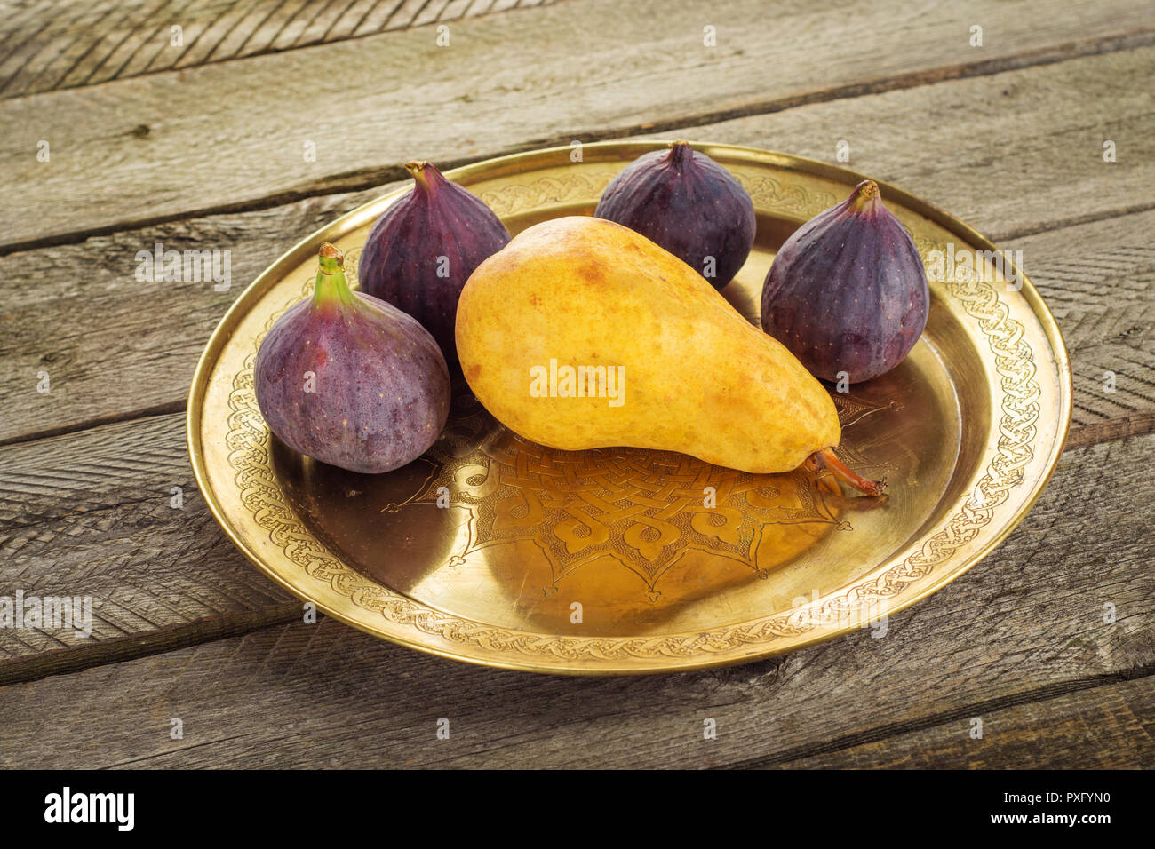 Group of figs and pear on vintage copper dish with traditional oriental ...