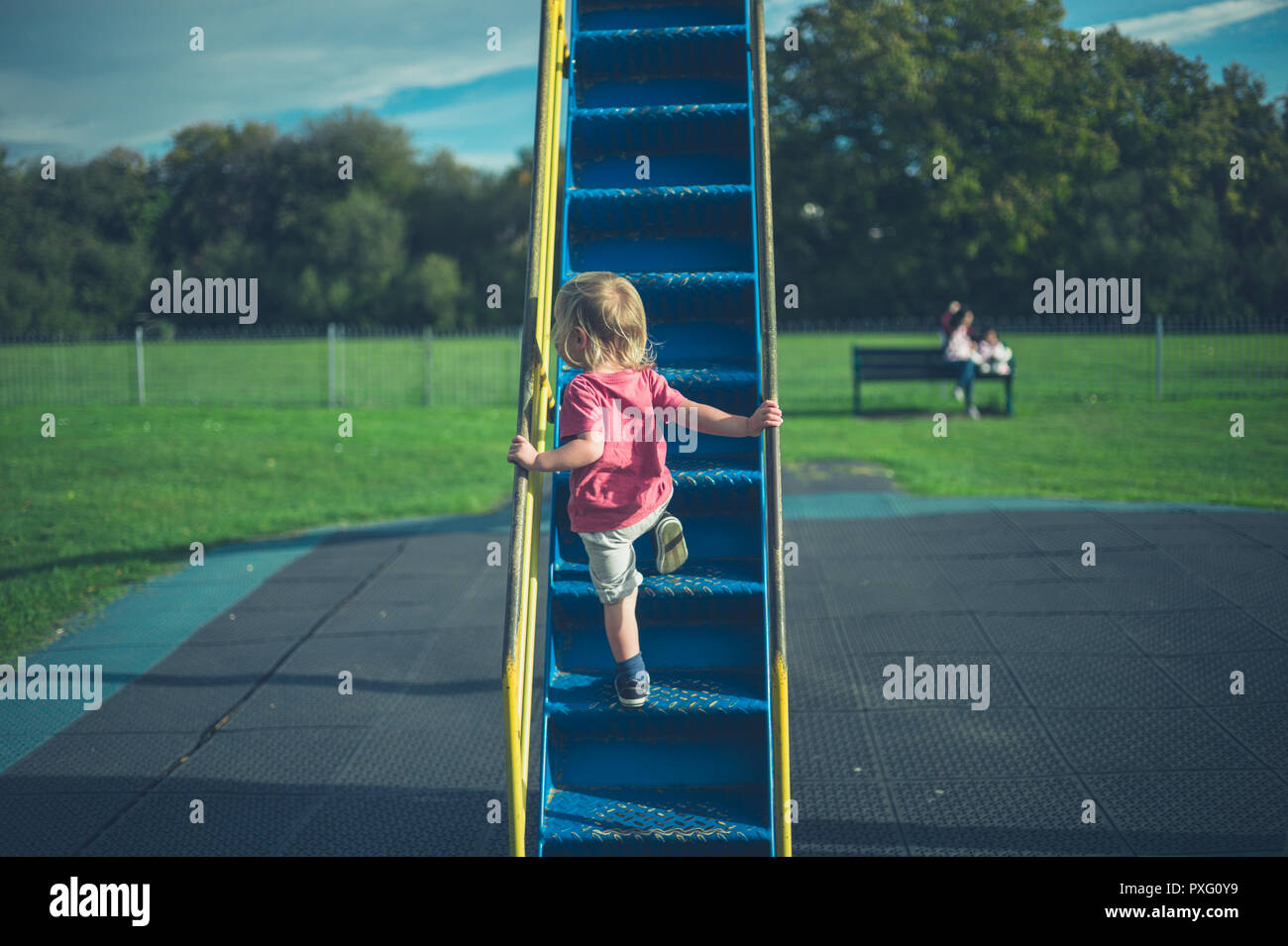 A little toddler is climbing up a slide Stock Photo - Alamy