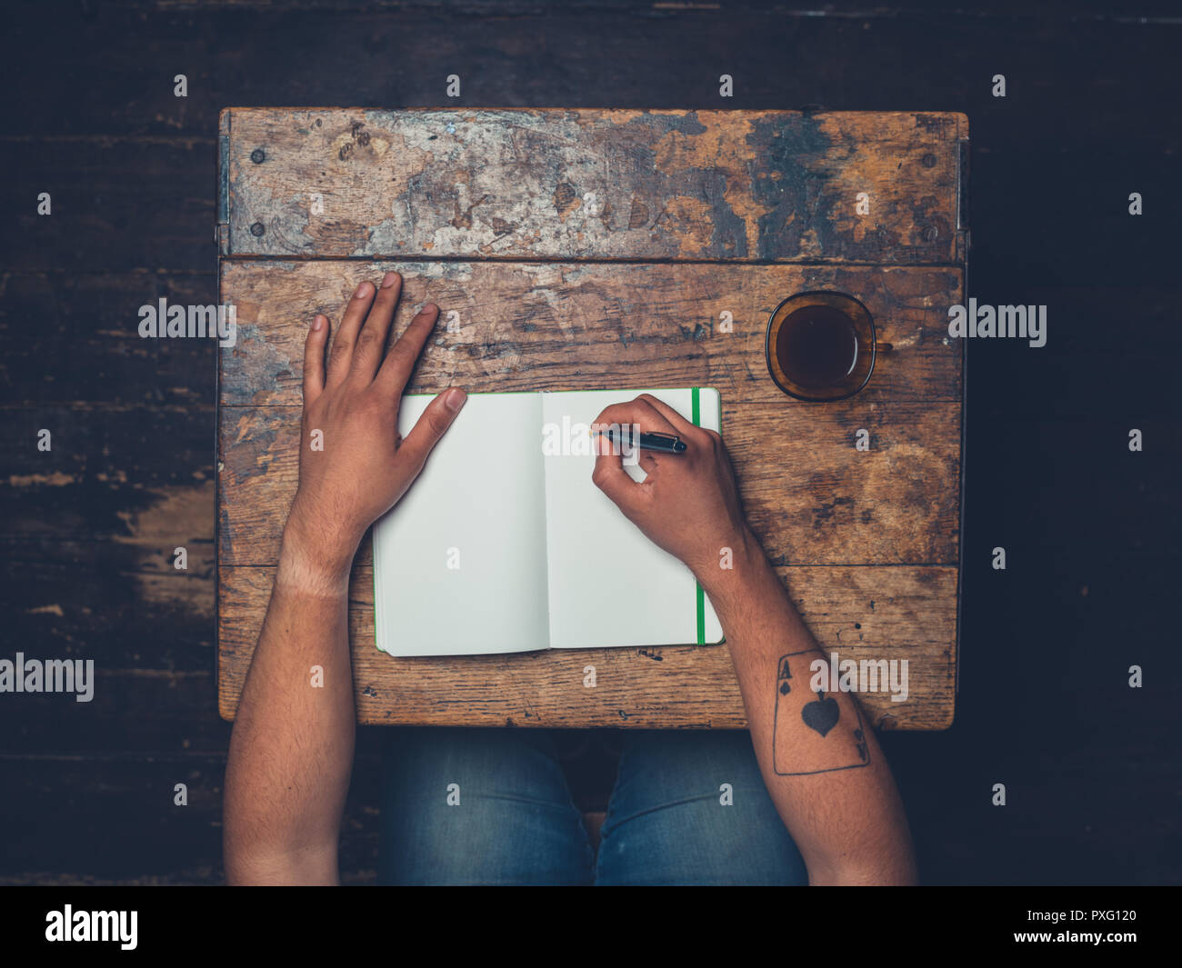 Overhead shot of man writing in notebook and drinking coffee Stock ...