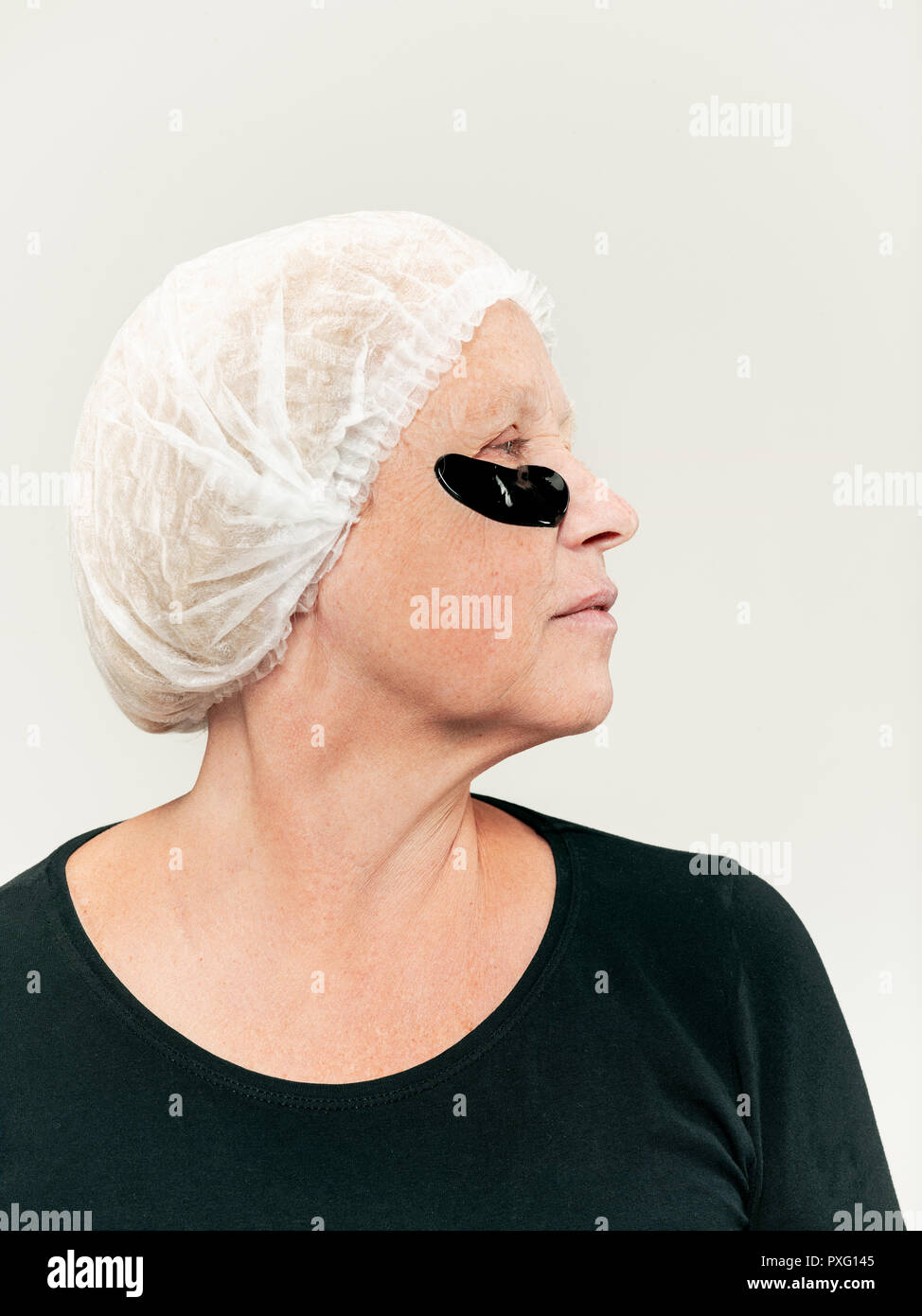 Senior woman isolated on white wall looking at camera making masks ...