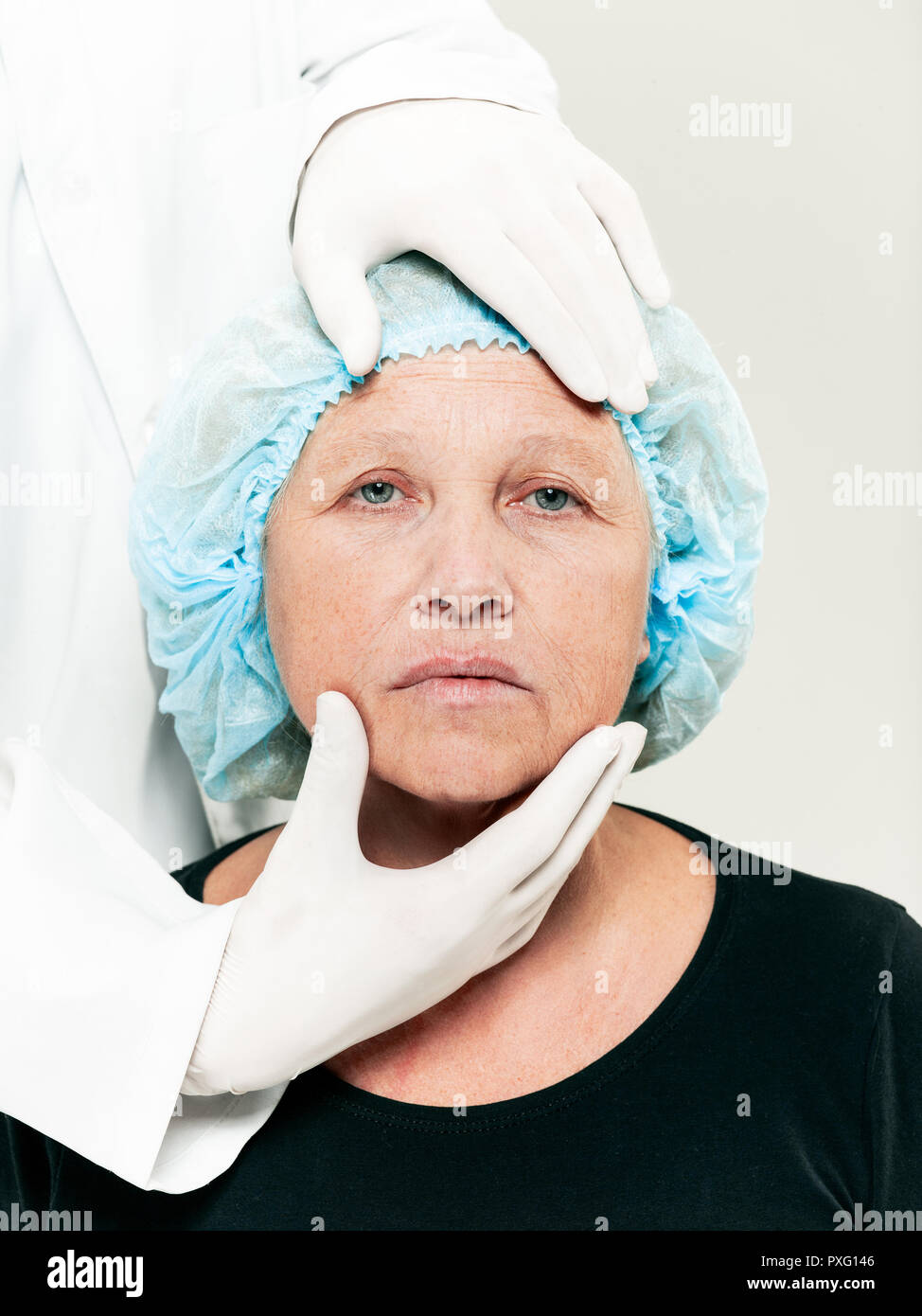 The surgeon doing skin check on mid age woman before plastic surgery ...