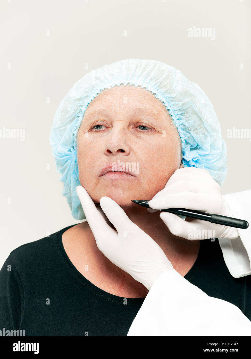 The surgeon doing skin check on mid age woman before plastic surgery ...