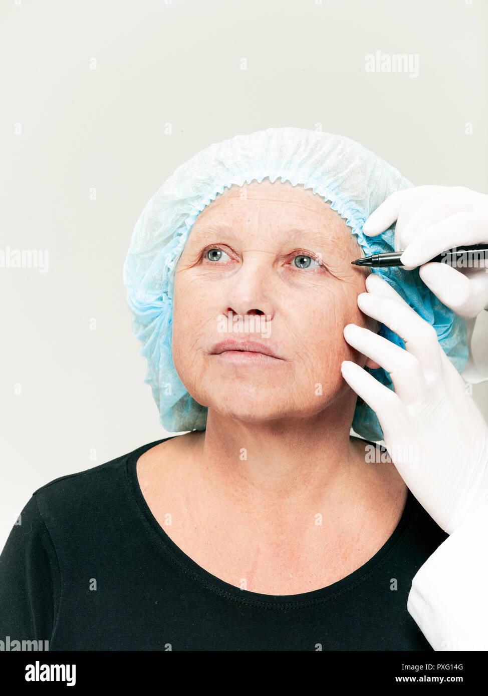 The surgeon doing skin check on mid age woman before plastic surgery ...