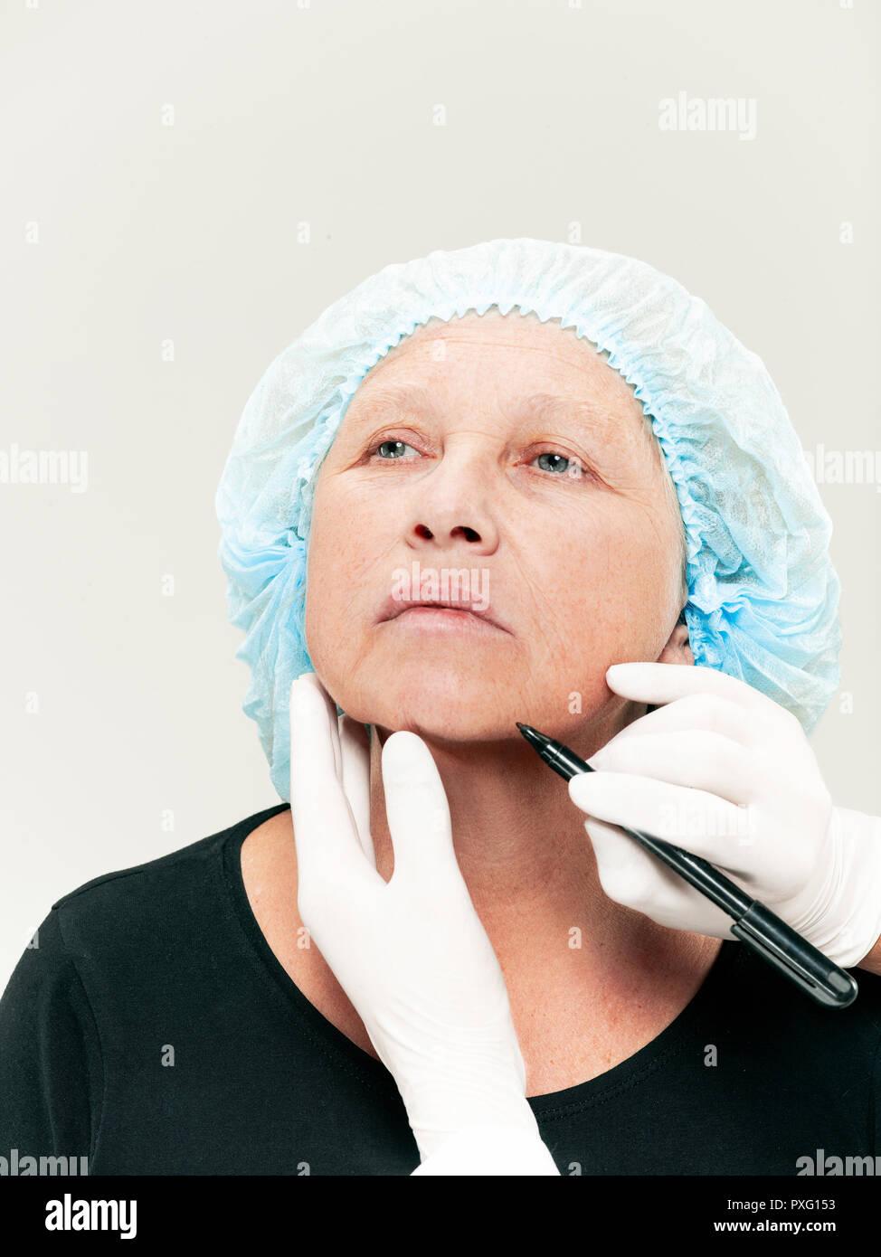 The surgeon doing skin check on mid age woman before plastic surgery ...