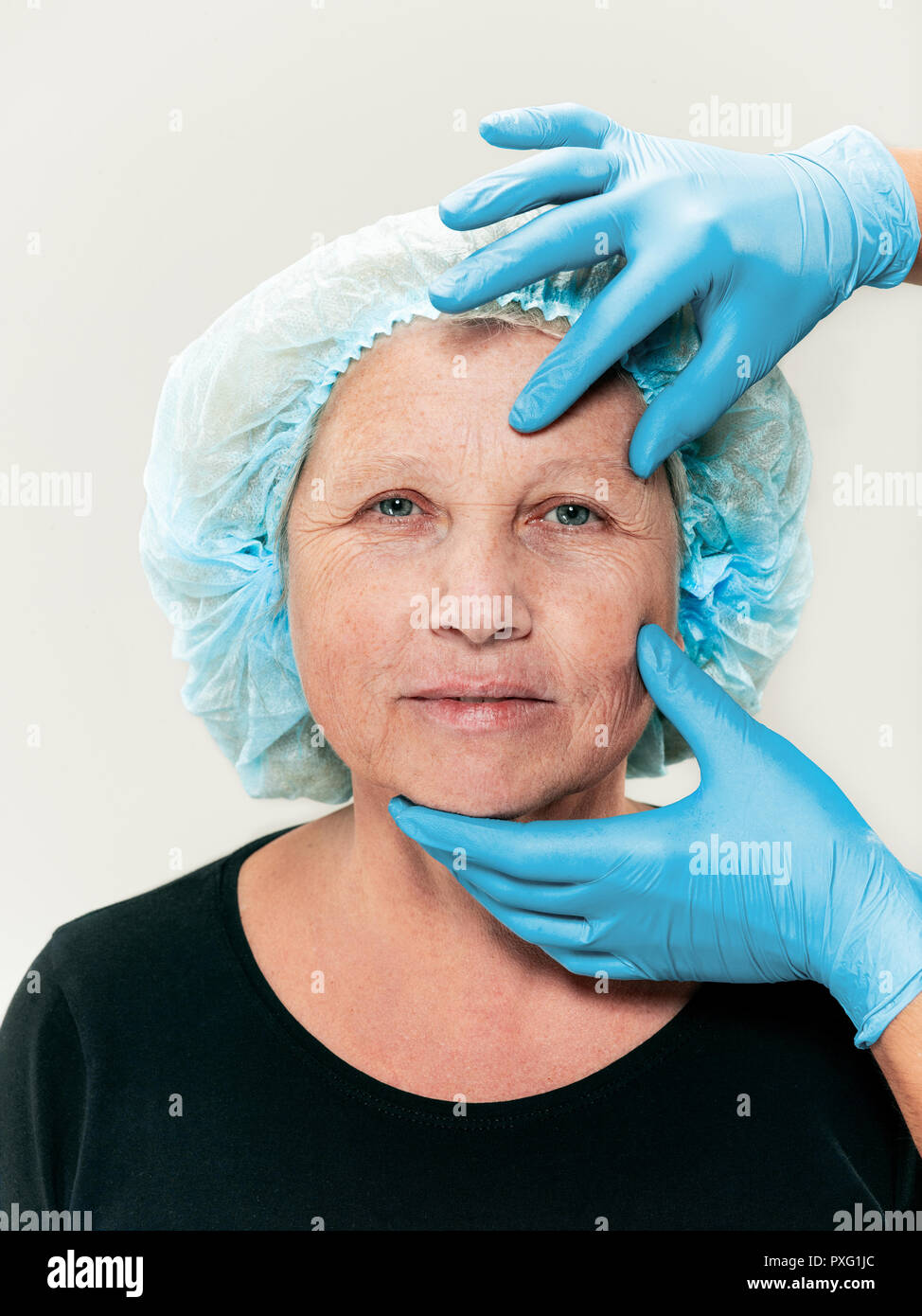 The surgeon doing skin check on mid age woman before plastic surgery ...