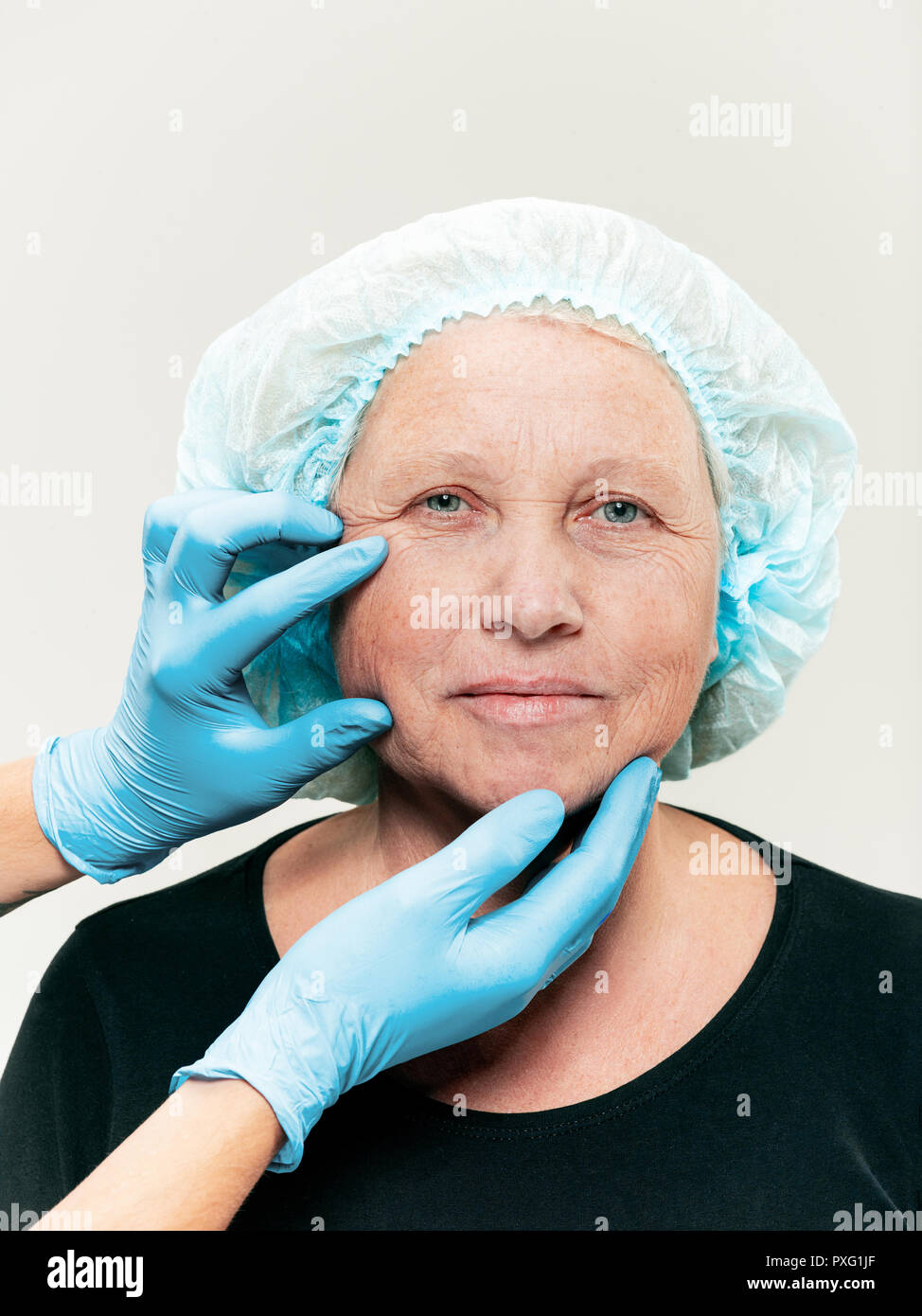 The surgeon doing skin check on mid age woman before plastic surgery ...