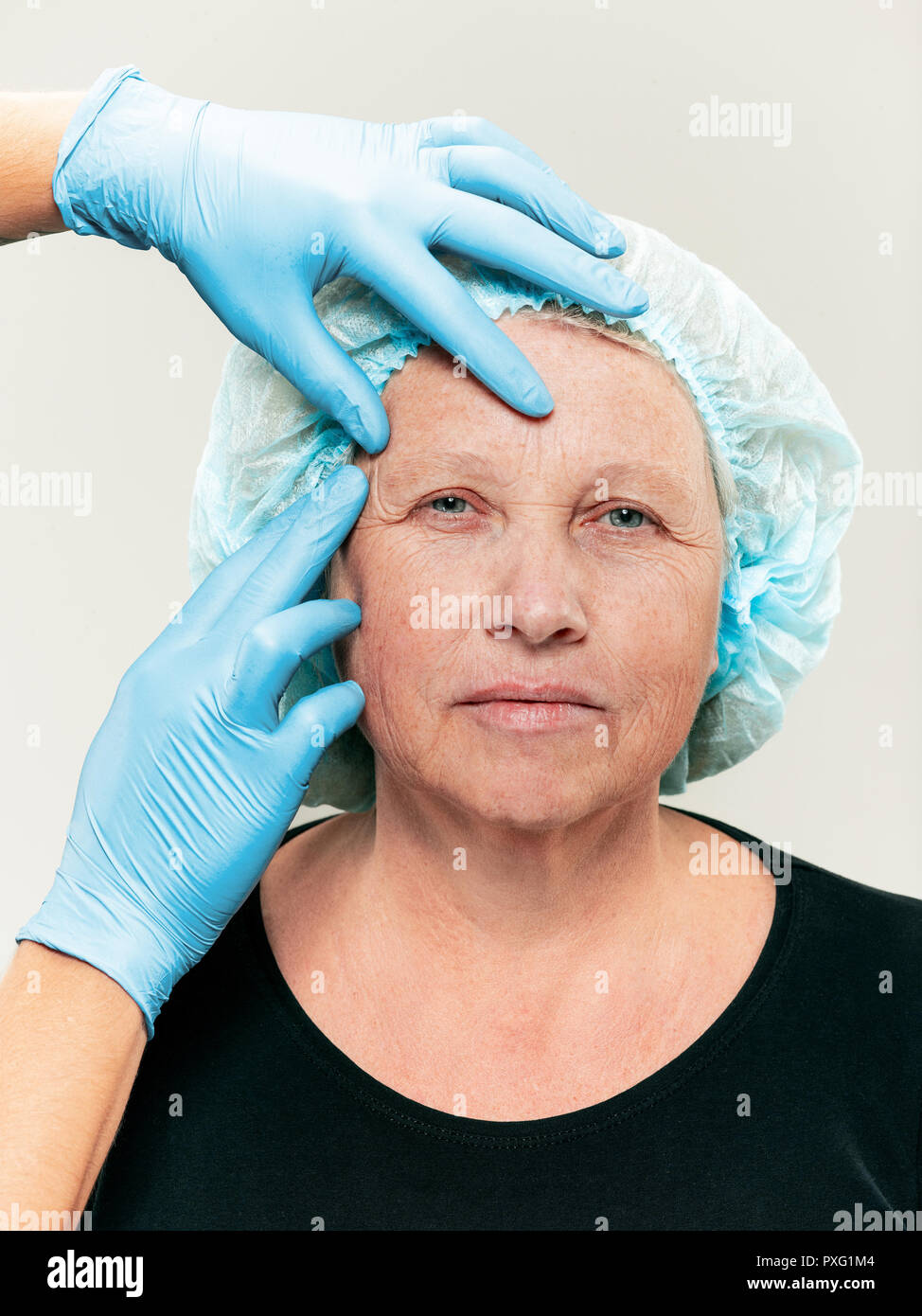 The surgeon doing skin check on mid age woman before plastic surgery ...