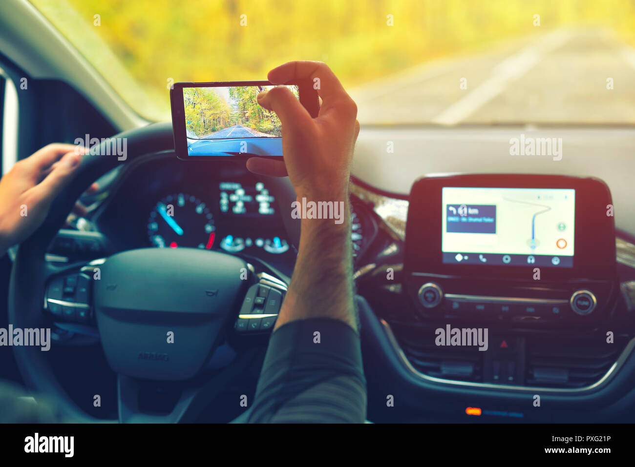 Male driver using smartphone to capture pictures of road, while driving ...