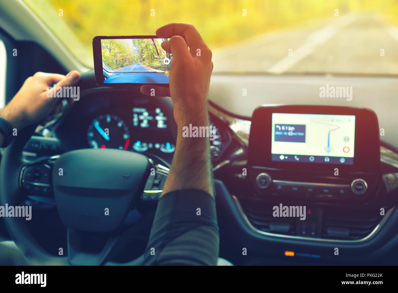 Male driver using smartphone to capture pictures of road, while driving ...