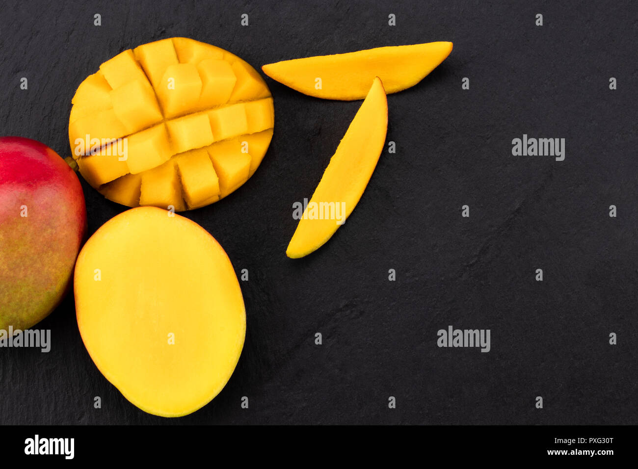 top view of ripe mango cut in half and diced on dark slate Stock Photo ...