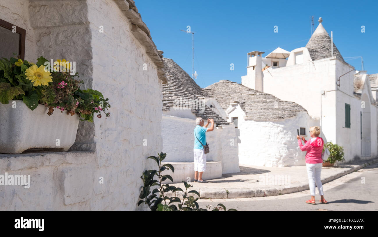 Tourists in the Italian town of Alberobello, looking at and ...