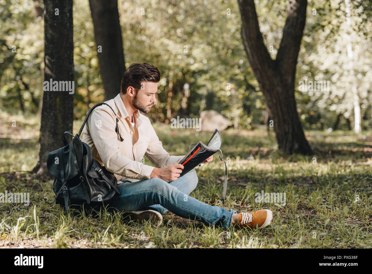 side view of traveler with map and backpack in park Stock Photo - Alamy