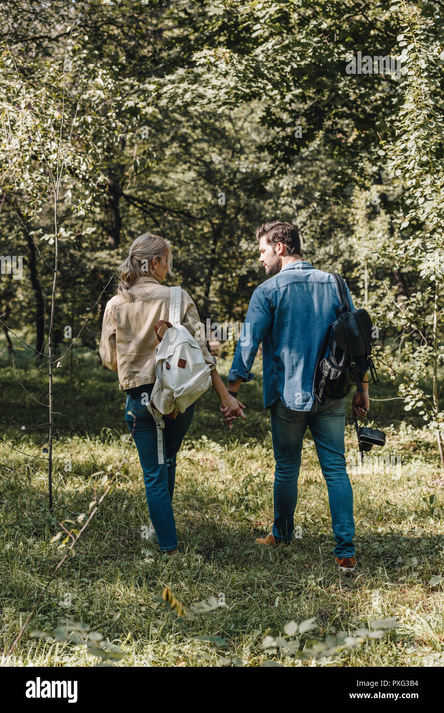 back view of romantic couple with backpacks holding hands in park Stock ...