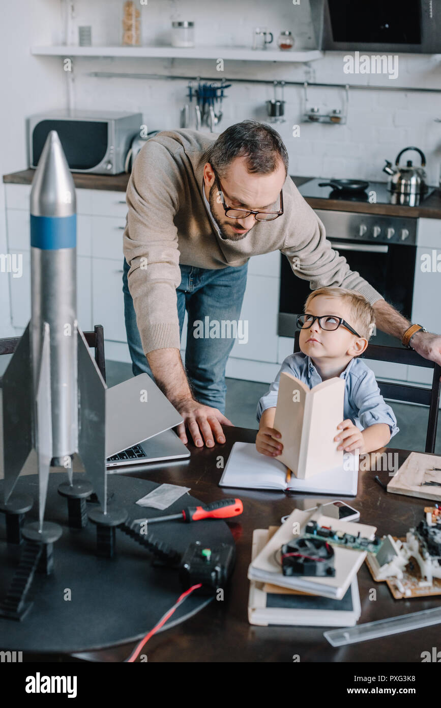 father and son modeling rocket and looking at each other at home Stock ...