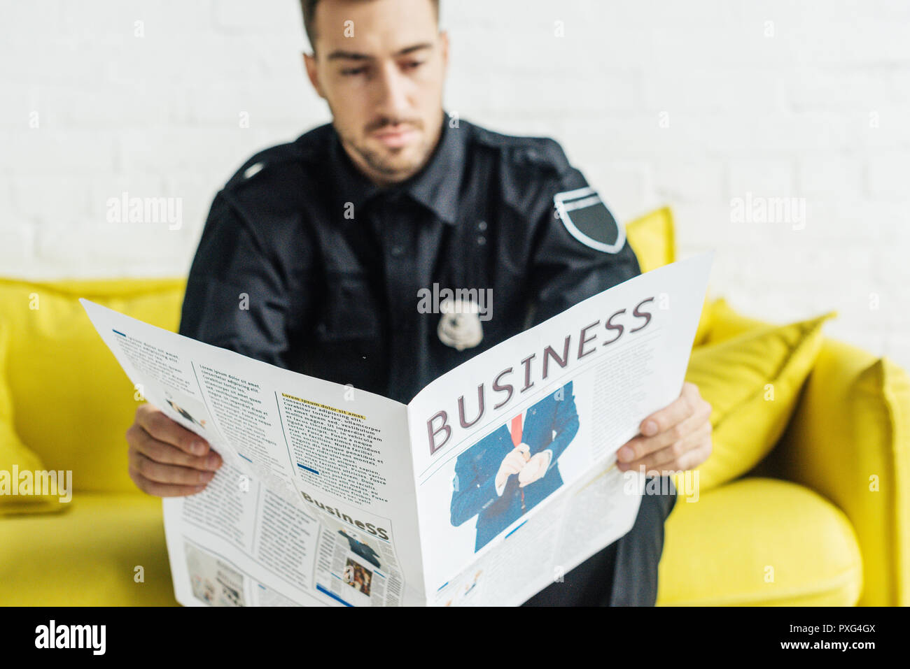 handsome young policeman reading newspaper on couch Stock Photo - Alamy