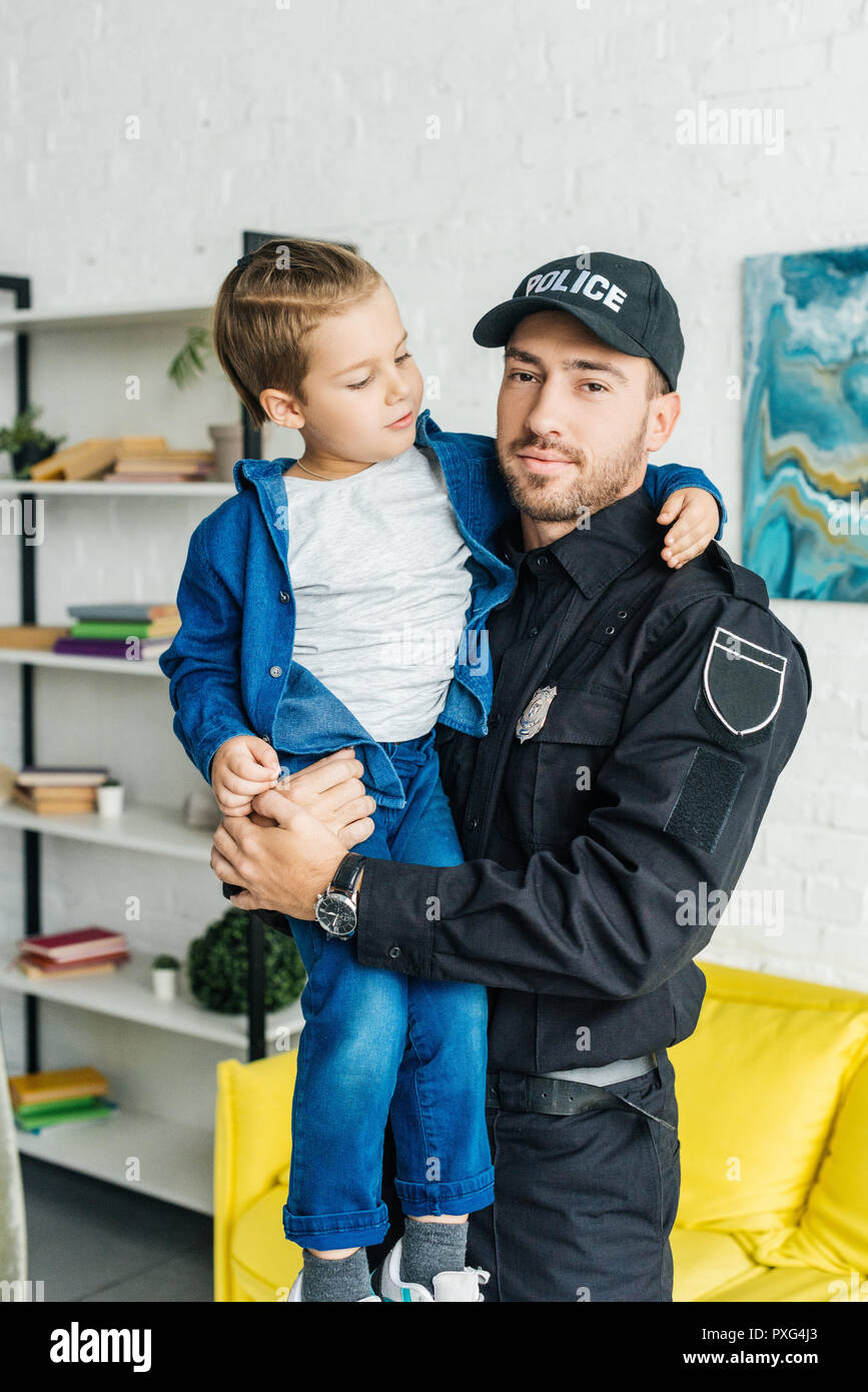 handsome young father in police uniform carrying his little son and ...