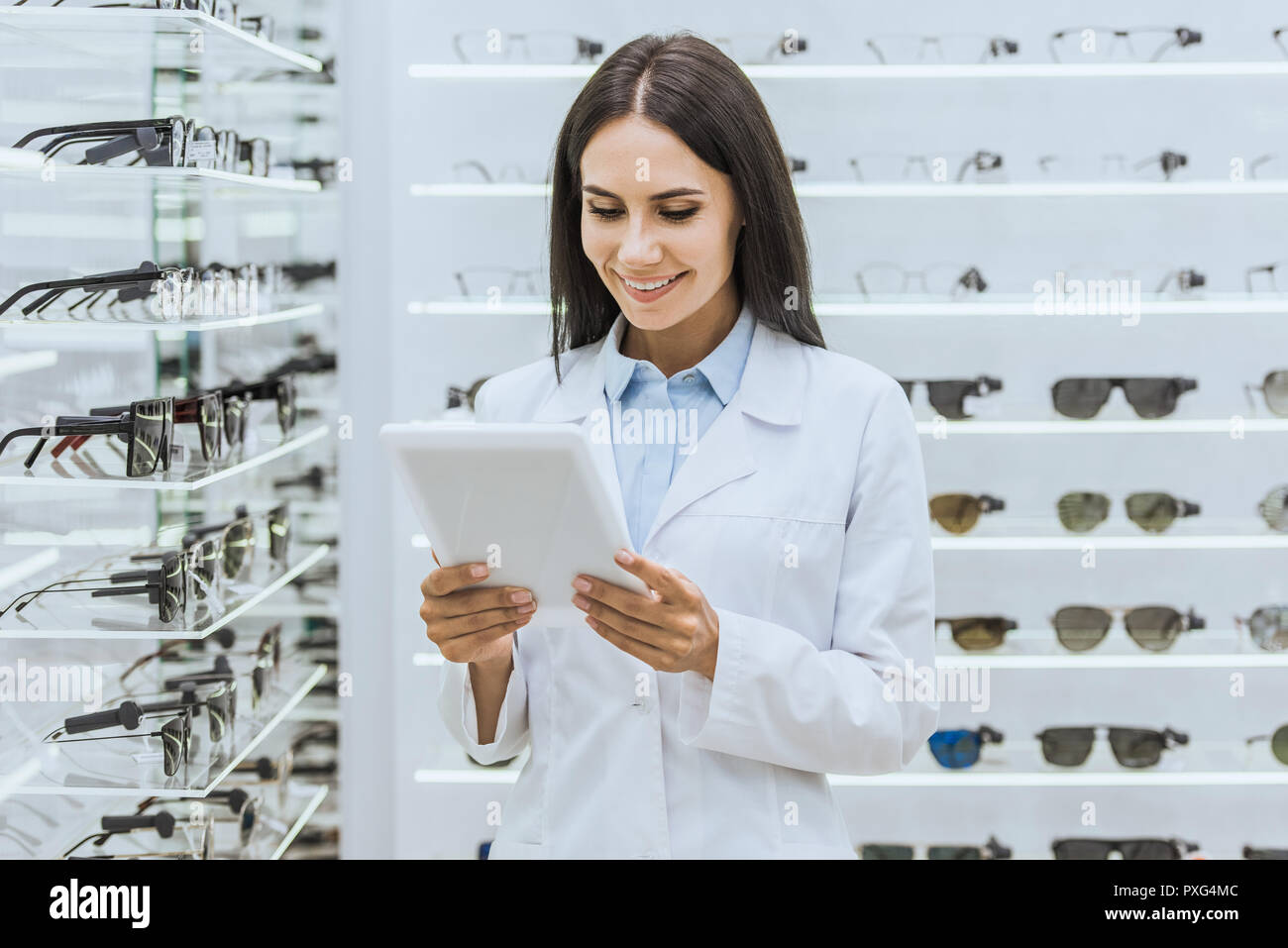beautiful female optometrist using digital tablet near shelves with ...