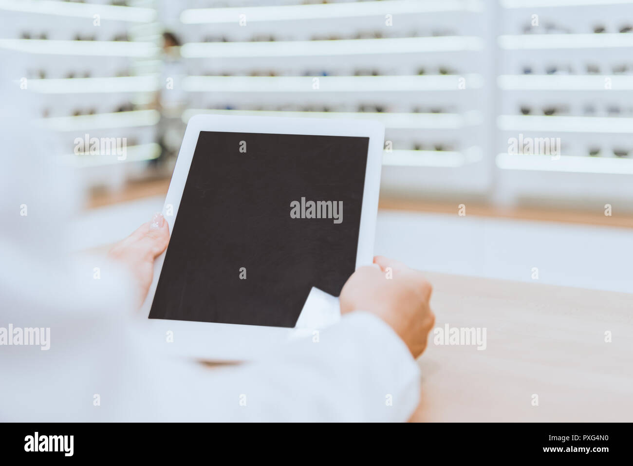 partial view of optician using digital tablet with blank screen at work ...