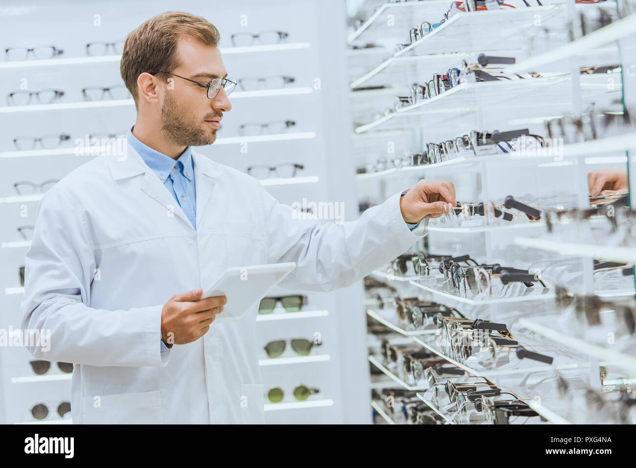 professional optician with tablet taking glasses from shelves in optica ...