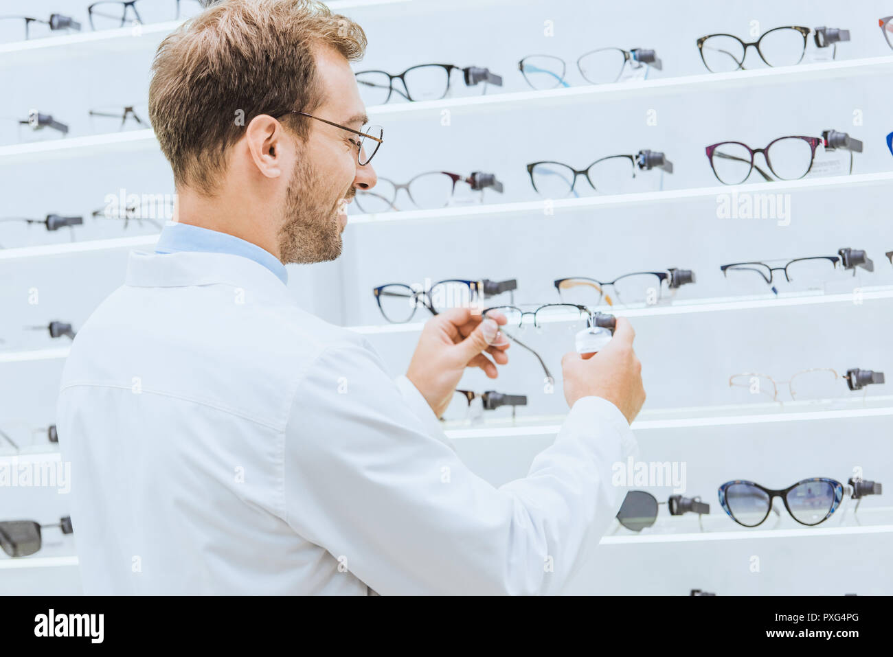 oculist taking eyeglasses from shelves in ophthalmic shop Stock Photo ...