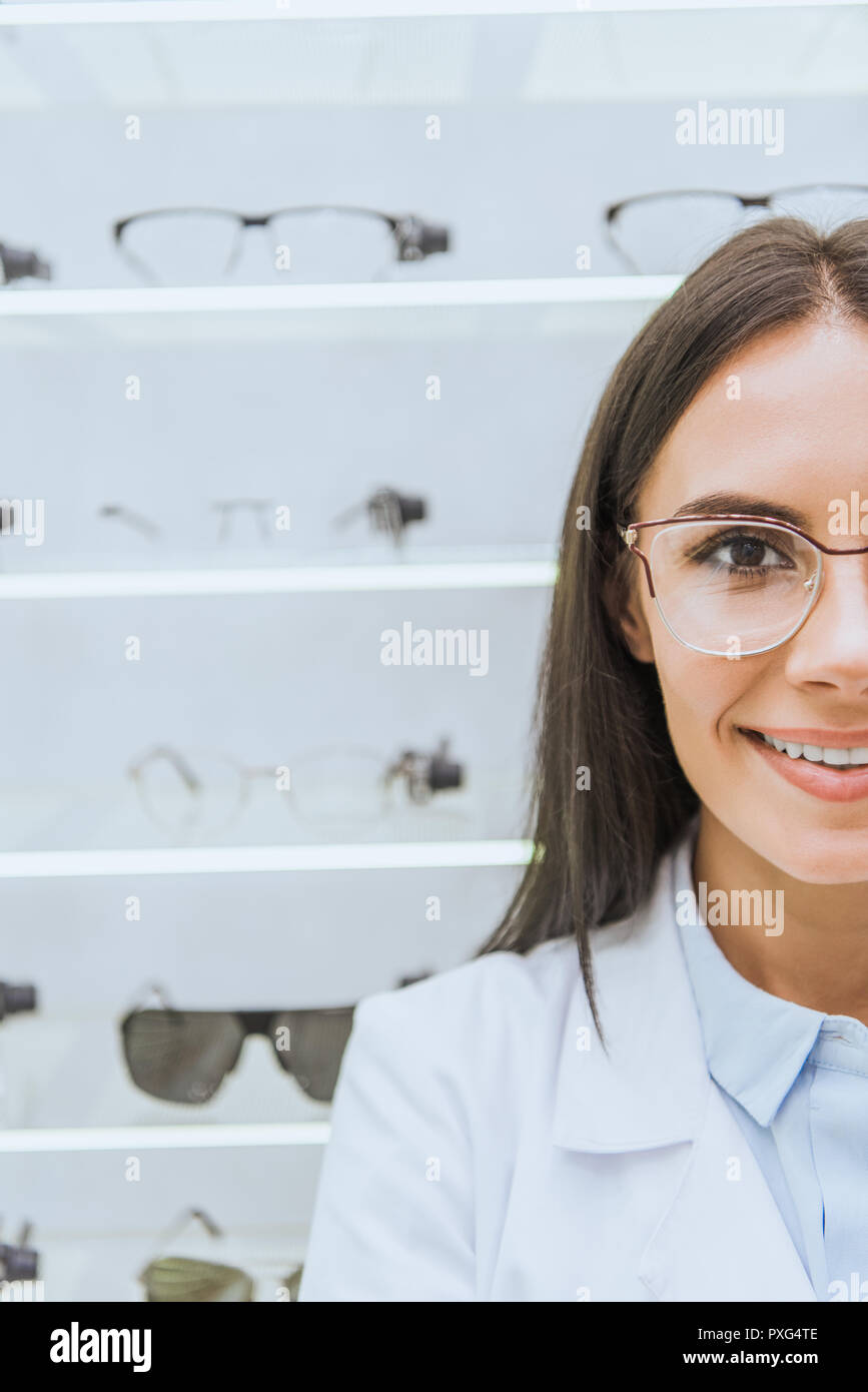 beautiful smiling optician in eyeglasses standing in ophthalmic shop ...