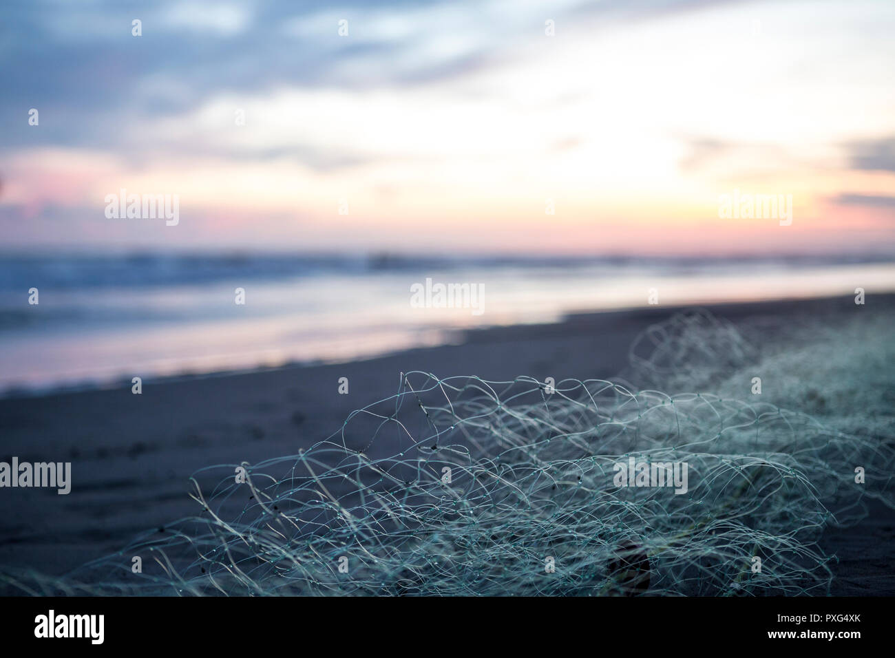 Fishing net on beach at sunset Stock Photo - Alamy
