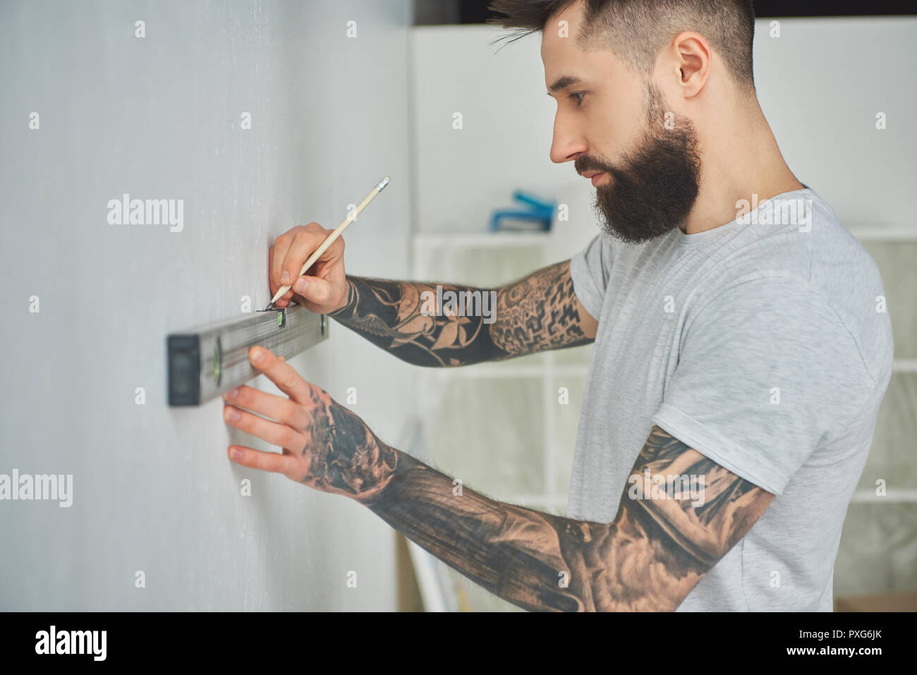 side view of handsome bearded young man holding level tool and pencil ...