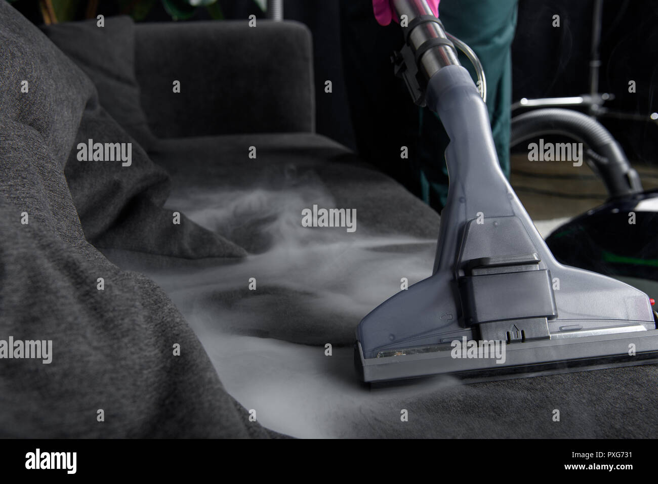 close-up view of person cleaning sofa with vacuum cleaner, hot steam ...