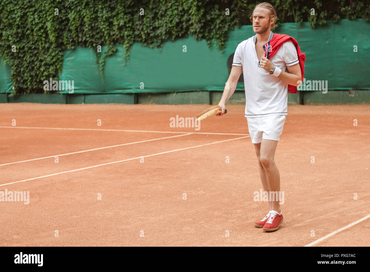 handsome man in sportswear with retro wooden racket on tennis court ...