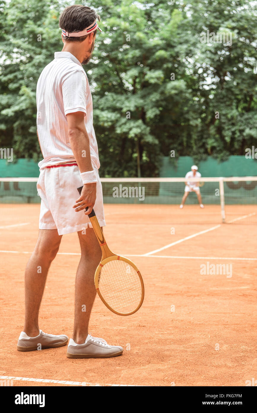 back view of man playing tennis with wooden racket on tennis court ...