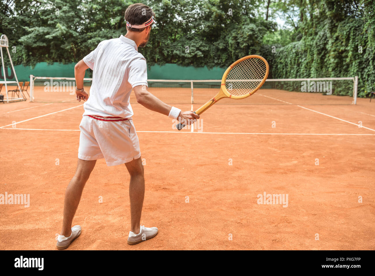 back view of tennis player with retro wooden racket on tennis court ...