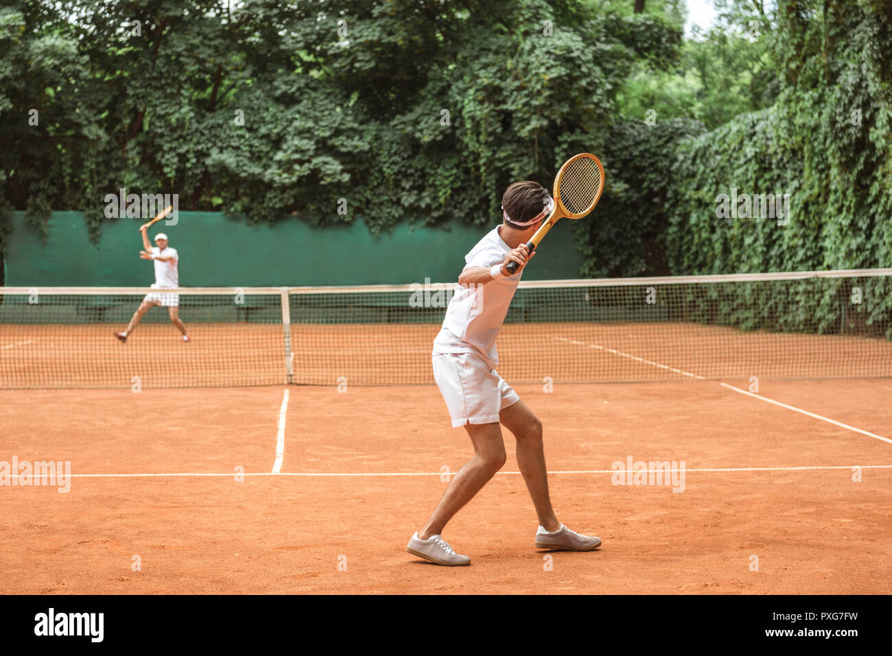 sportsmen in white sportswear playing tennis with wooden rackets on ...