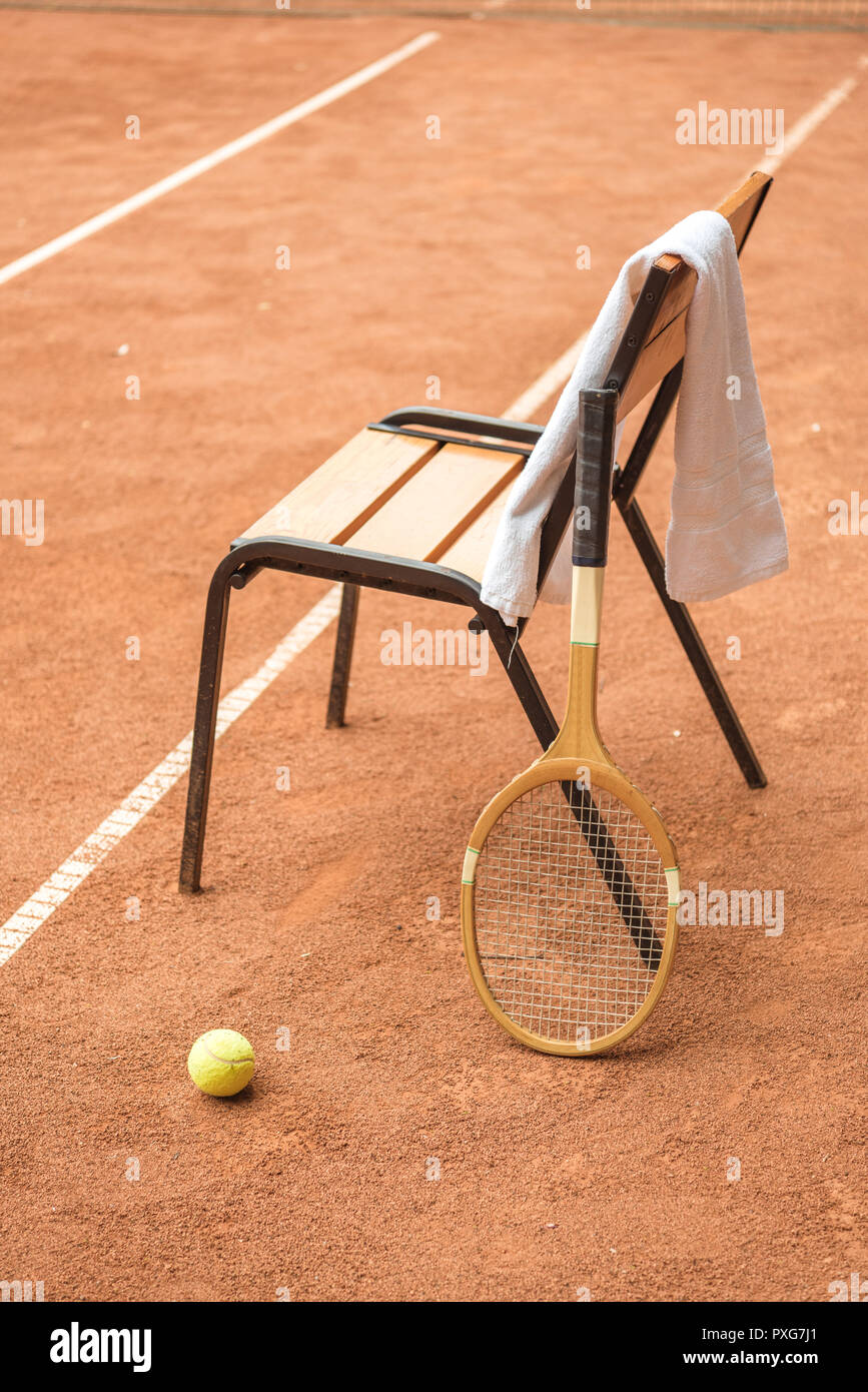 close up of chair with tennis ball, retro wooden racket and towel on ...