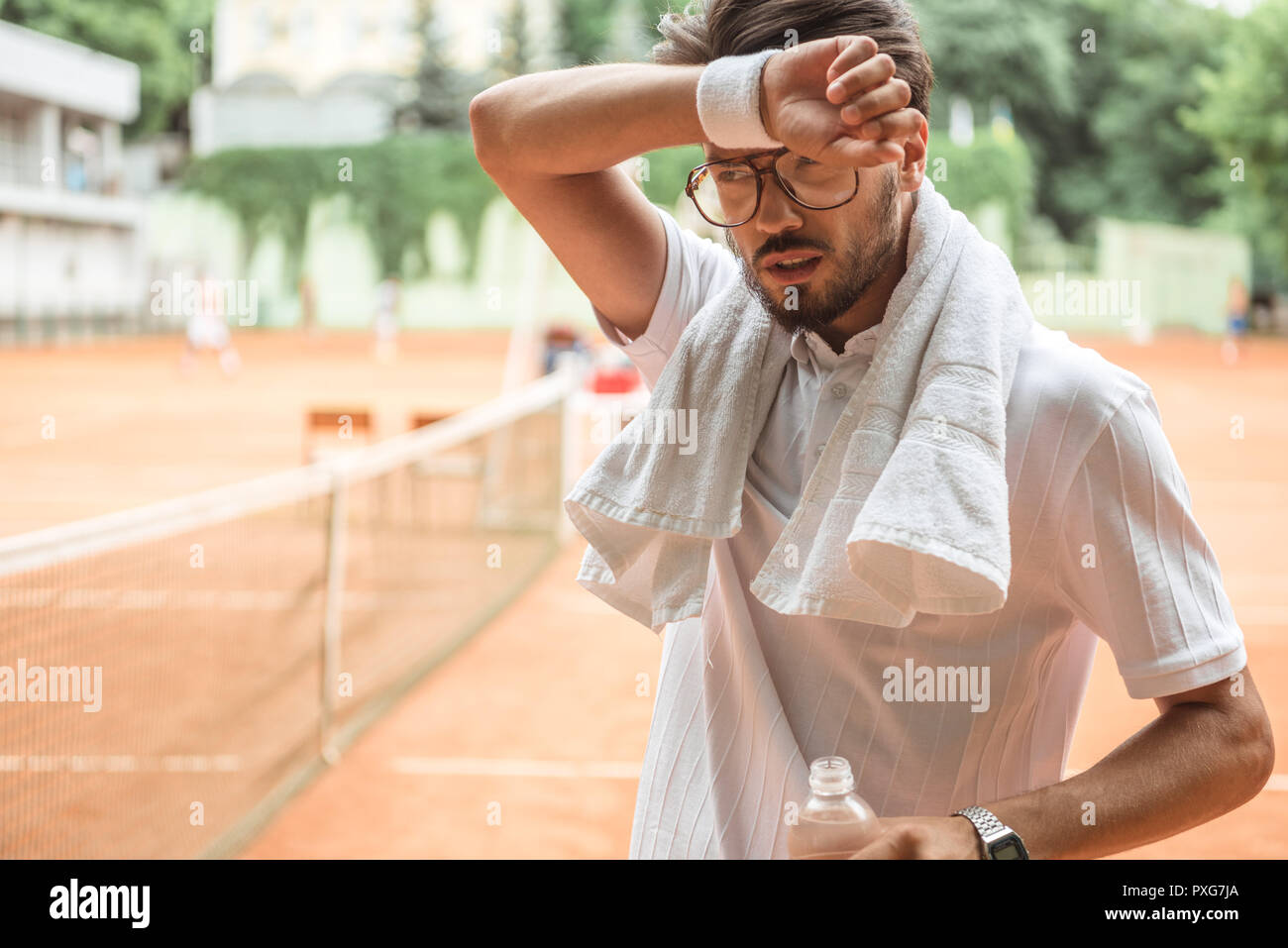 sweaty tired tennis player with towel after training on tennis court ...